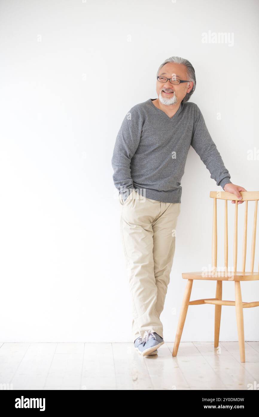 An elderly man standing with his hand on a chair Stock Photo - Alamy