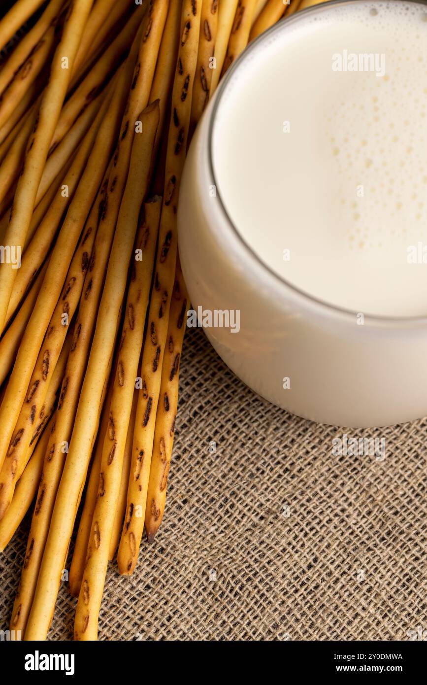 Thin and long bread sticks made of wheat flour and a glass of milk ...