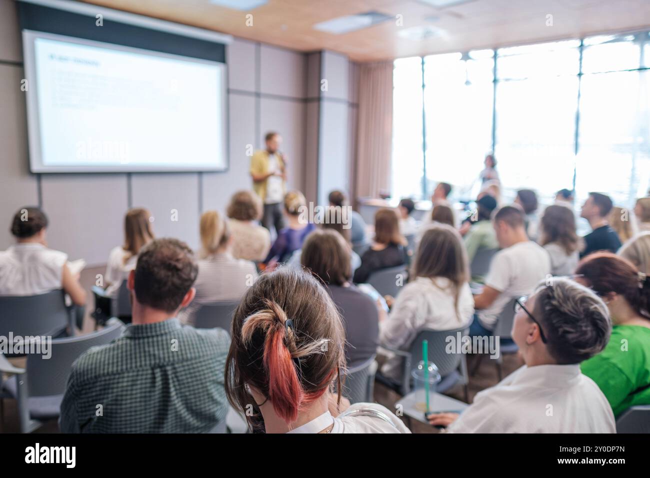 Group of people attending a presentation in a conference room. Speaker ...