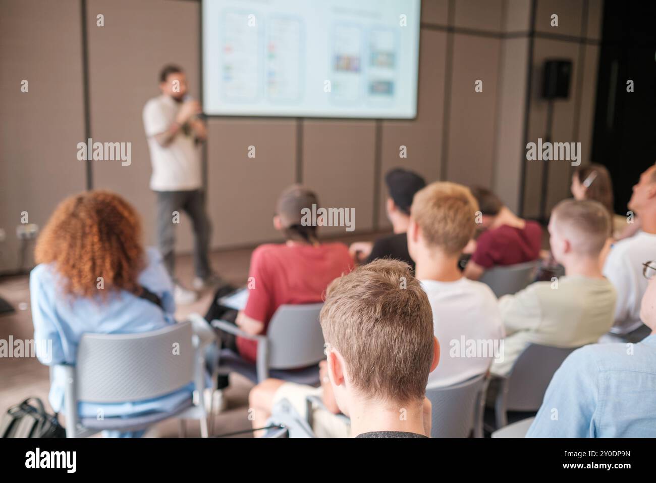 Group of people attending seminar, focusing on speaker presenting at ...