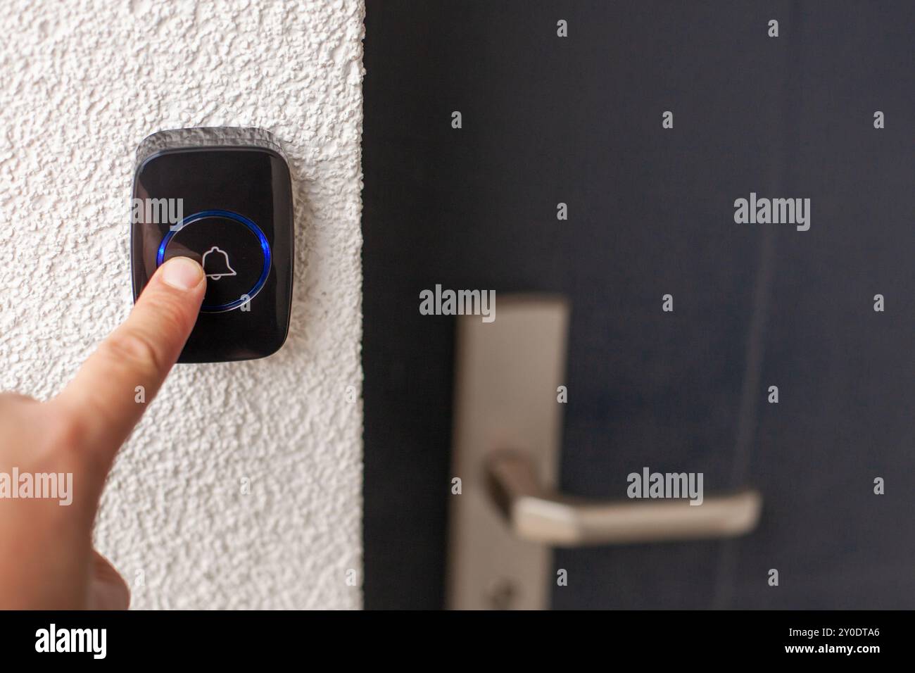 Pressing Black Doorbell with Blue Ring on White Wall Stock Photo - Alamy