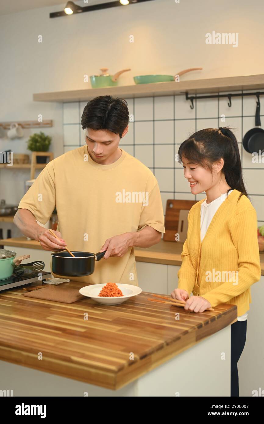 Happy asian couple cooking together in a modern kitchen and enjoying a ...