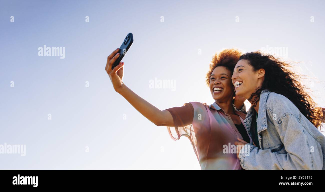 Happy female friends in their 20s taking a selfie together. Capturing ...