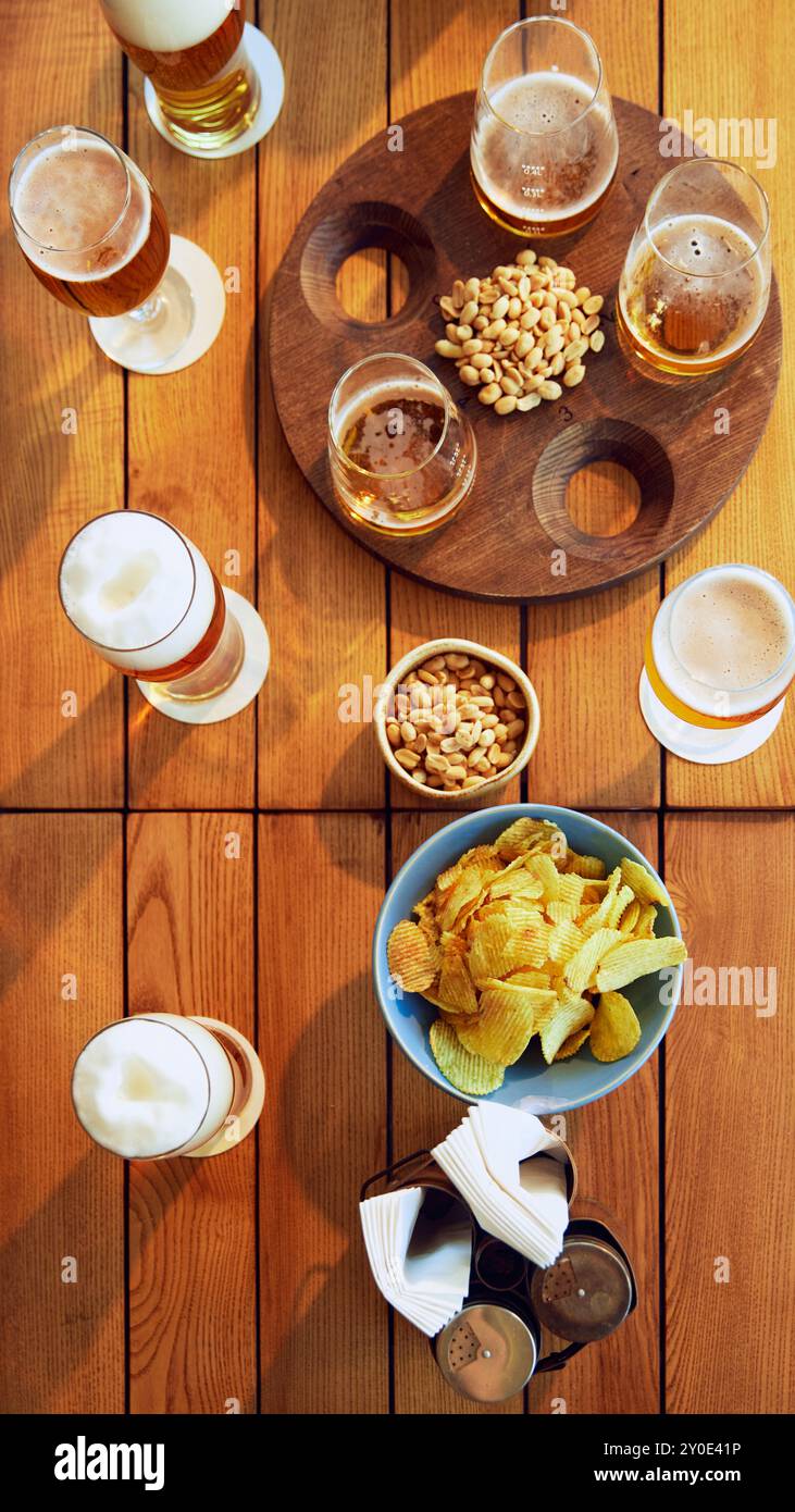Wooden table filled with various beers, nuts, and potato chips, viewed ...