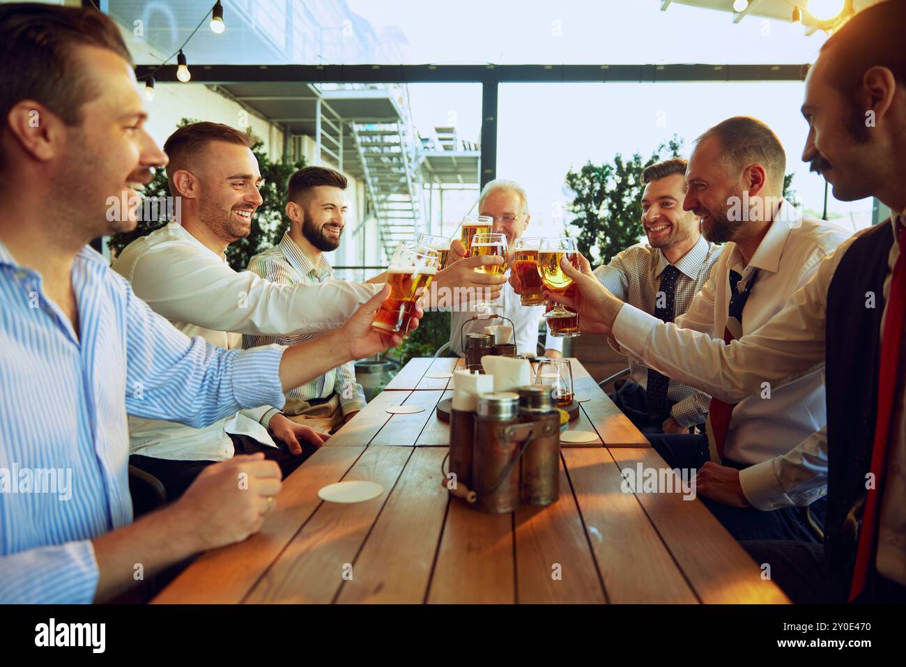 Group of smiling men, business people, colleagues sitting in pub and ...