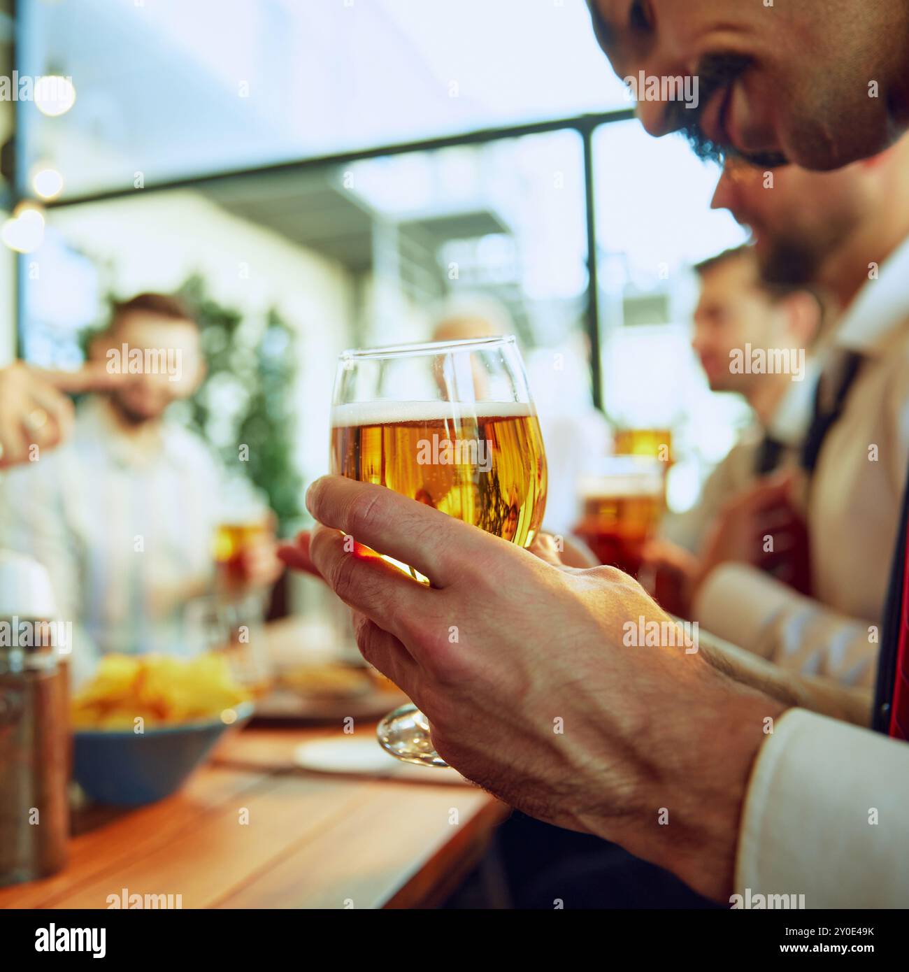 Focus on male hand holding lager beer. Business people, colleagues ...