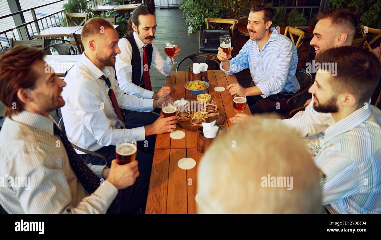Colleagues, businessmen relaxing at the bar with beers, balancing work ...