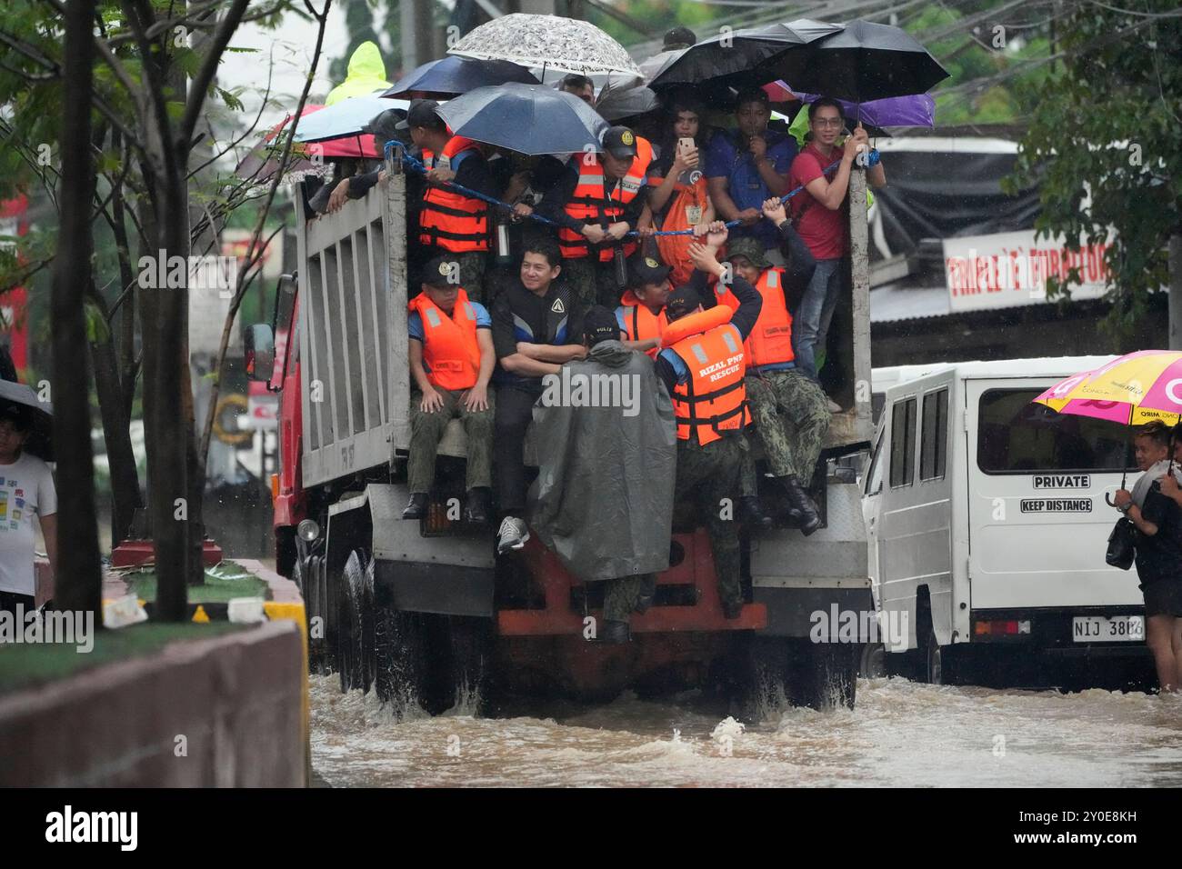 Rescuers and residents ride a truck as they cross a flooded street ...