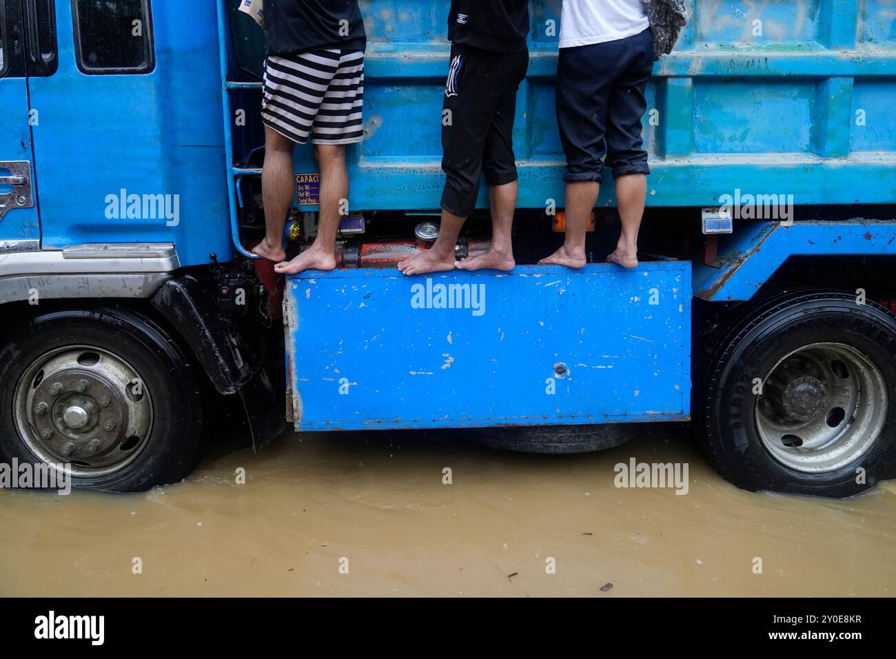 Residents ride a truck as they negotiate a flooded street caused by ...