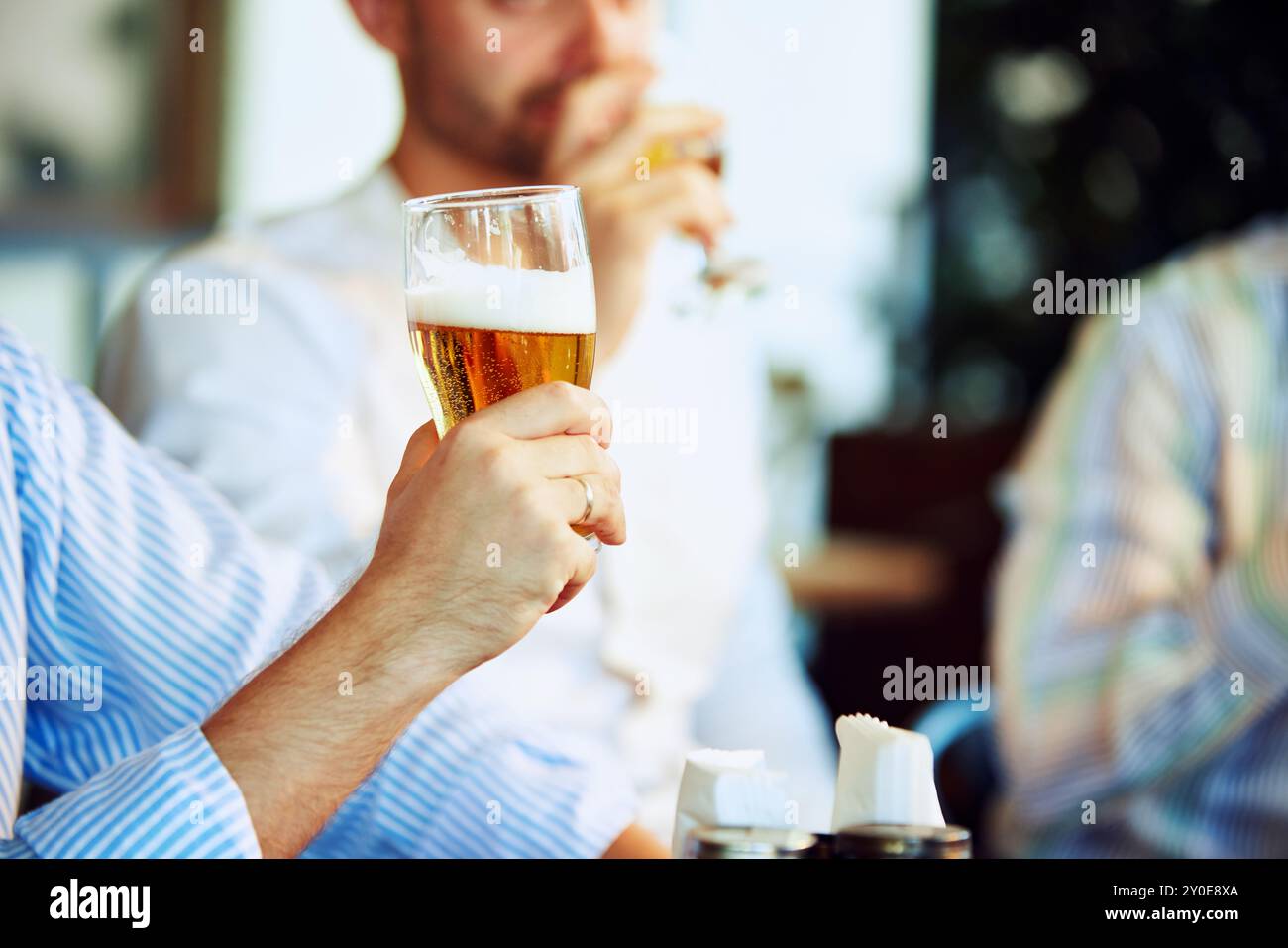 Focus on male hand holding glass of lager beer with thick foam ...