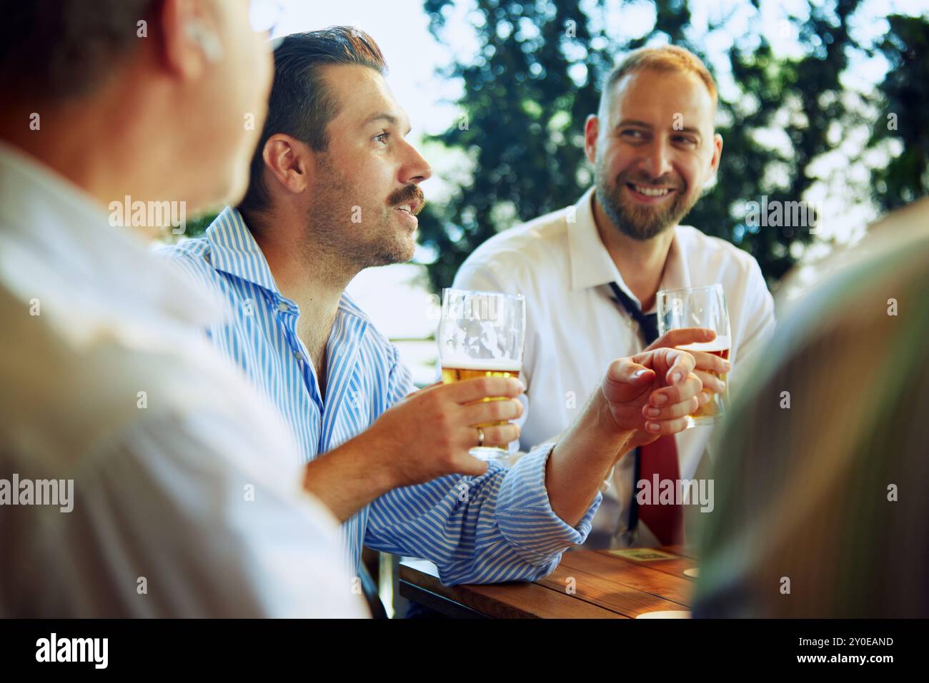 Cheerful people, businessmen, colleagues sitting at outdoor bar ...