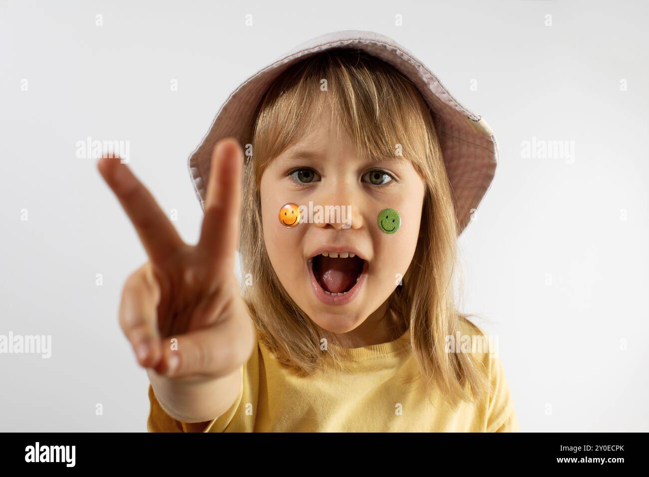 Little girl in hat shows peace gestures on light background Stock Photo ...