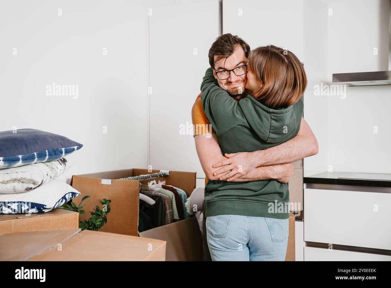 Couple hugs around moving boxes, man smiling an looking at camera,woman ...