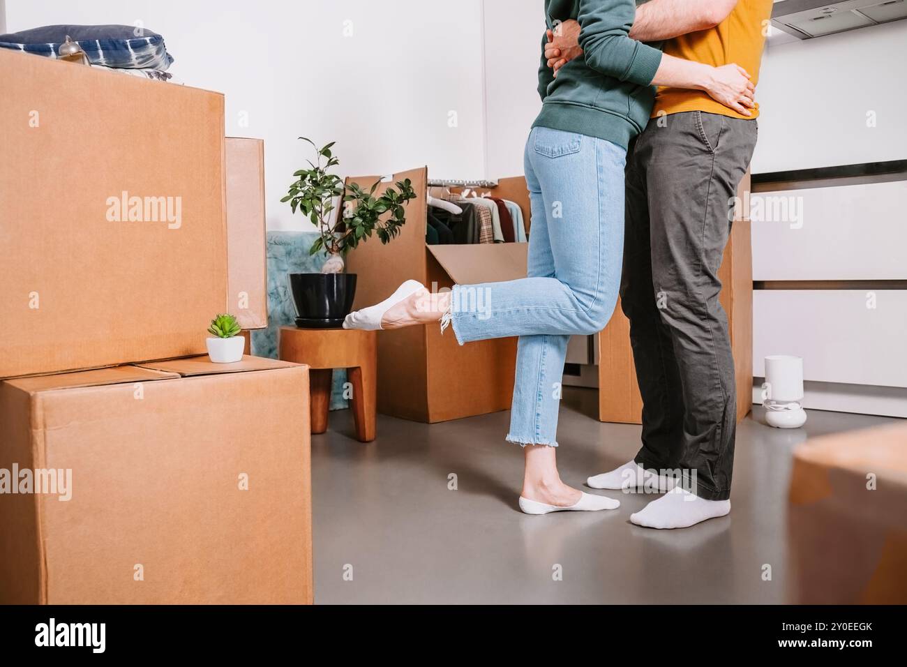 Couple is hugging closely with one leg lifted while standing amidst ...