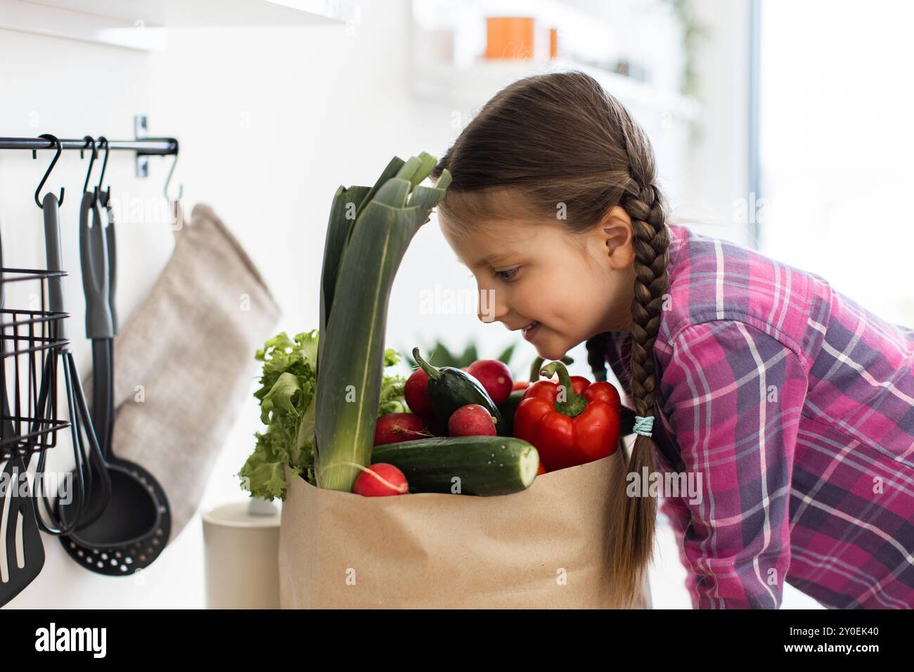 Girl examining fresh vegetables in kitchen with curiosity Stock Photo ...