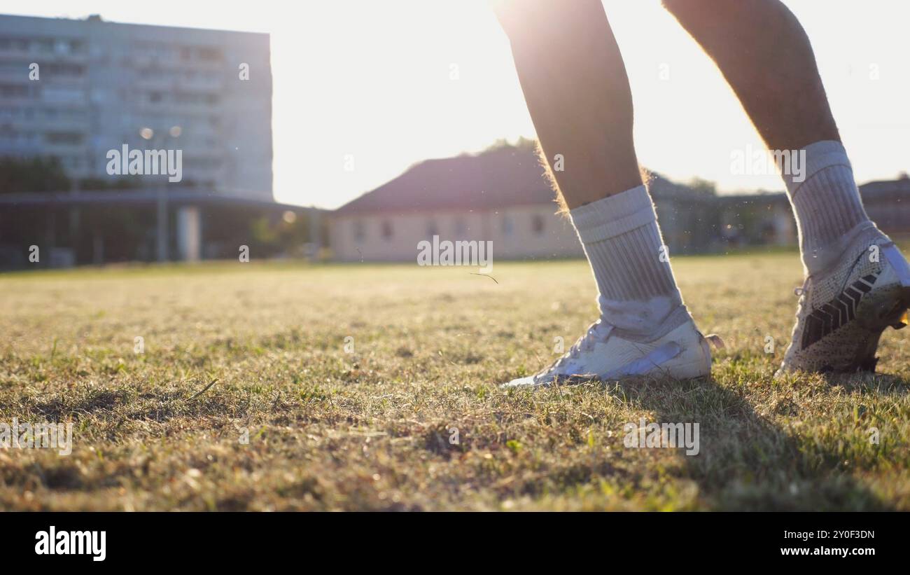 Legs of young man kicking ball at green field. Male feet of ...