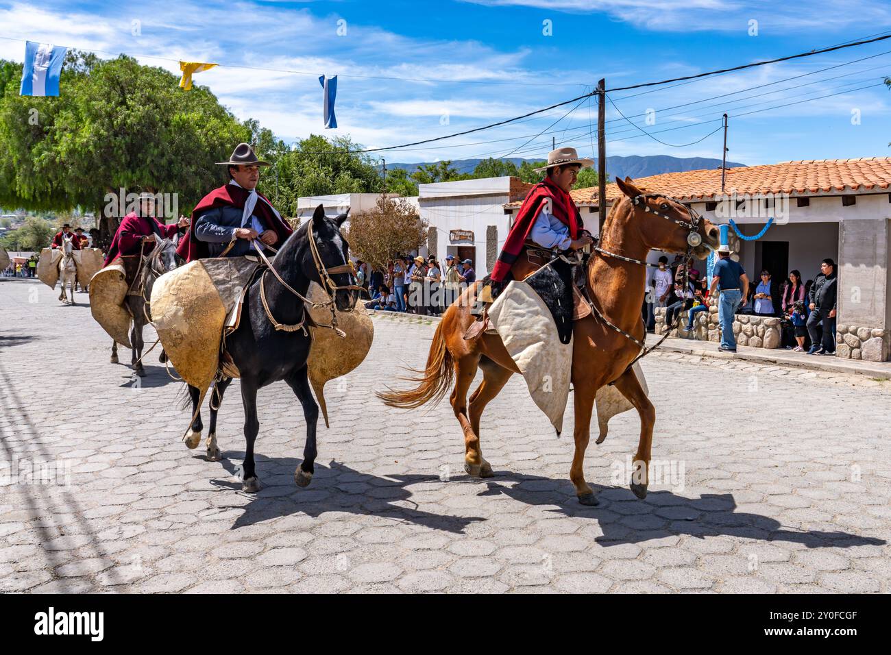 Gauchos in traditional outfits riding on horseback in a parade in Cachi ...