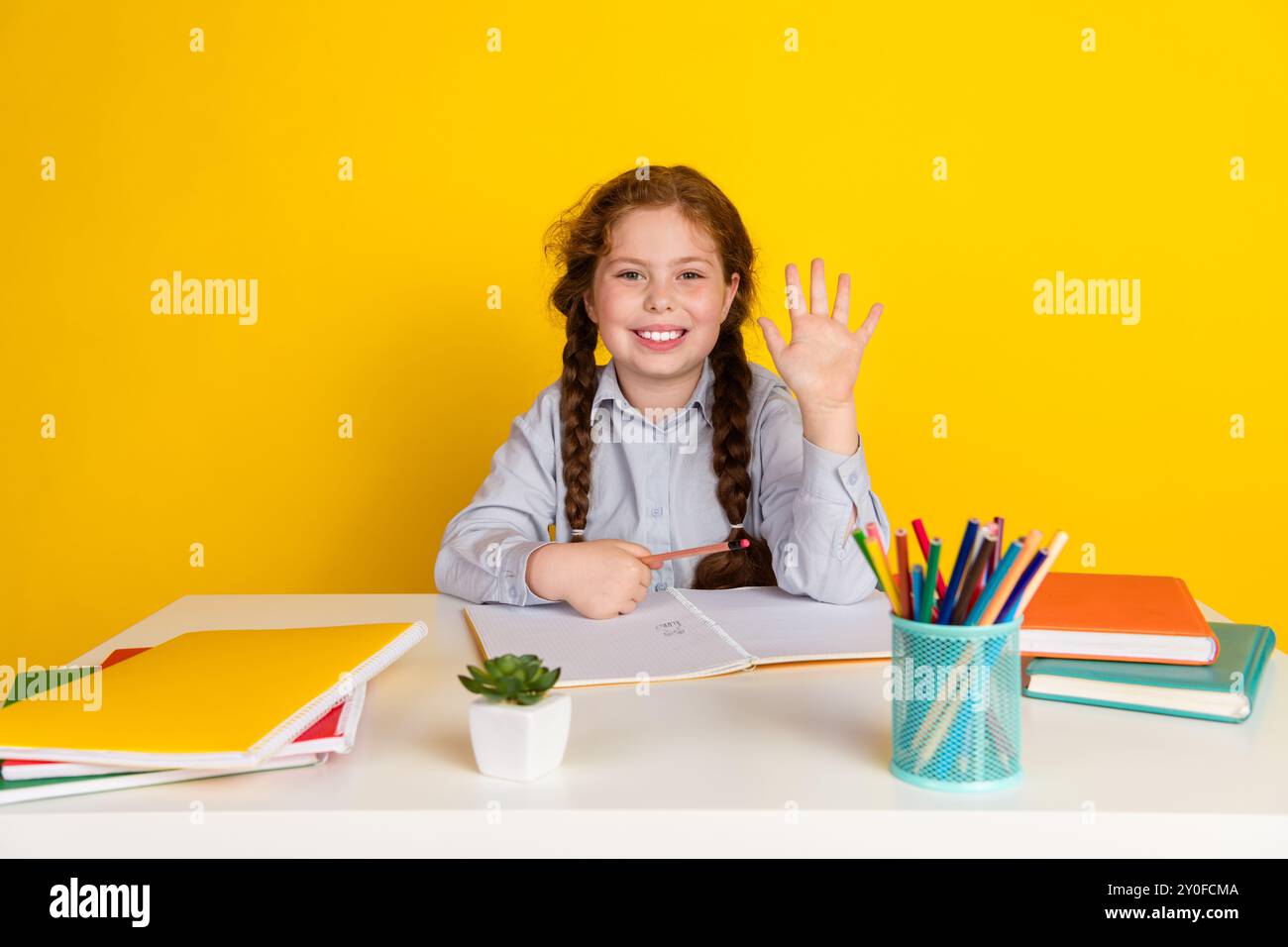 Portrait of little schoolchild girl desktop raise arm wave wear uniform ...