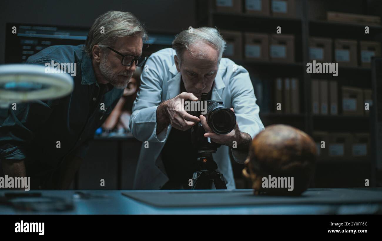 Two archaeologists talk and take photo of fossil remains of prehistoric ...