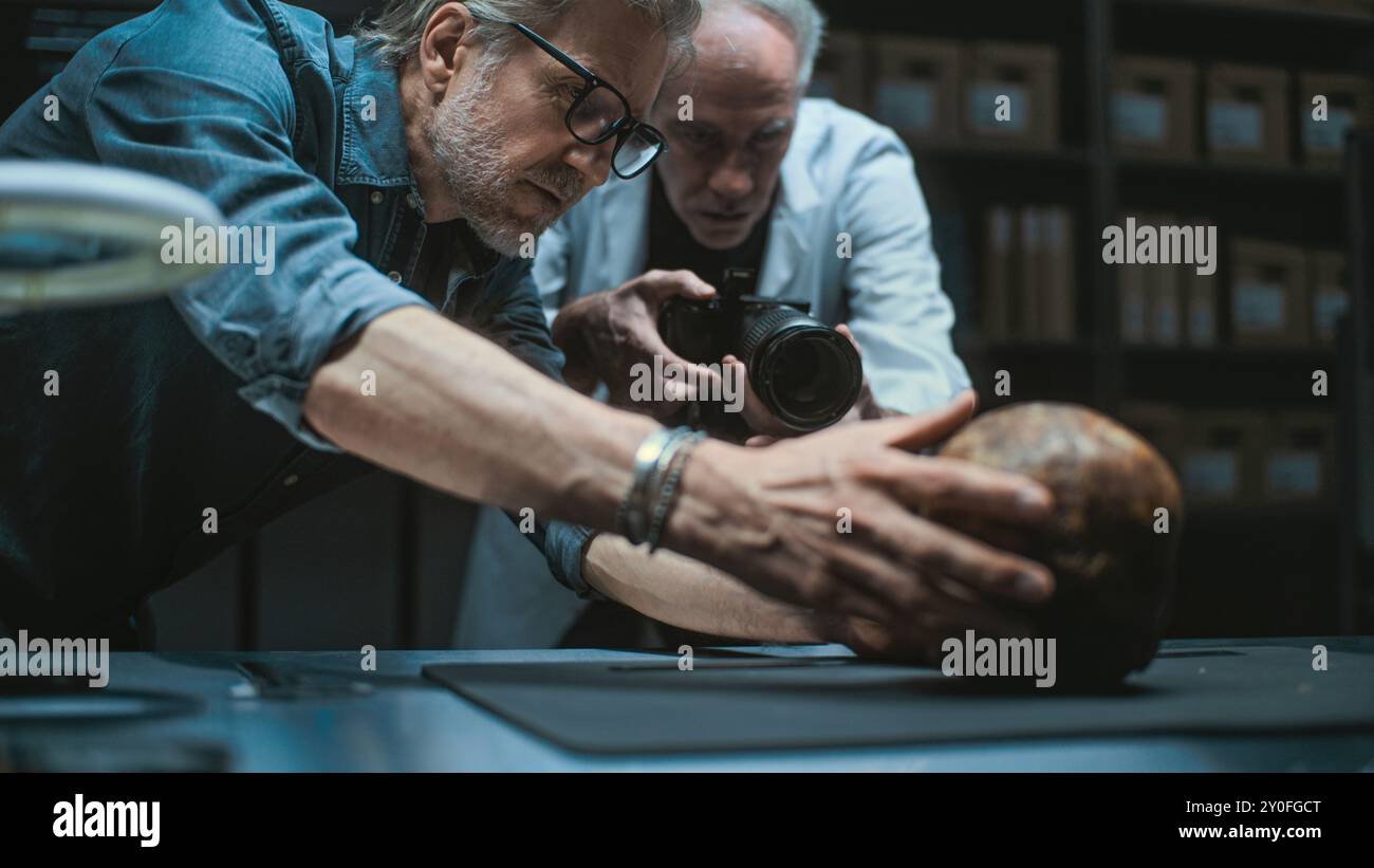 Two archaeologists talk and take photo of fossil remains of prehistoric ...