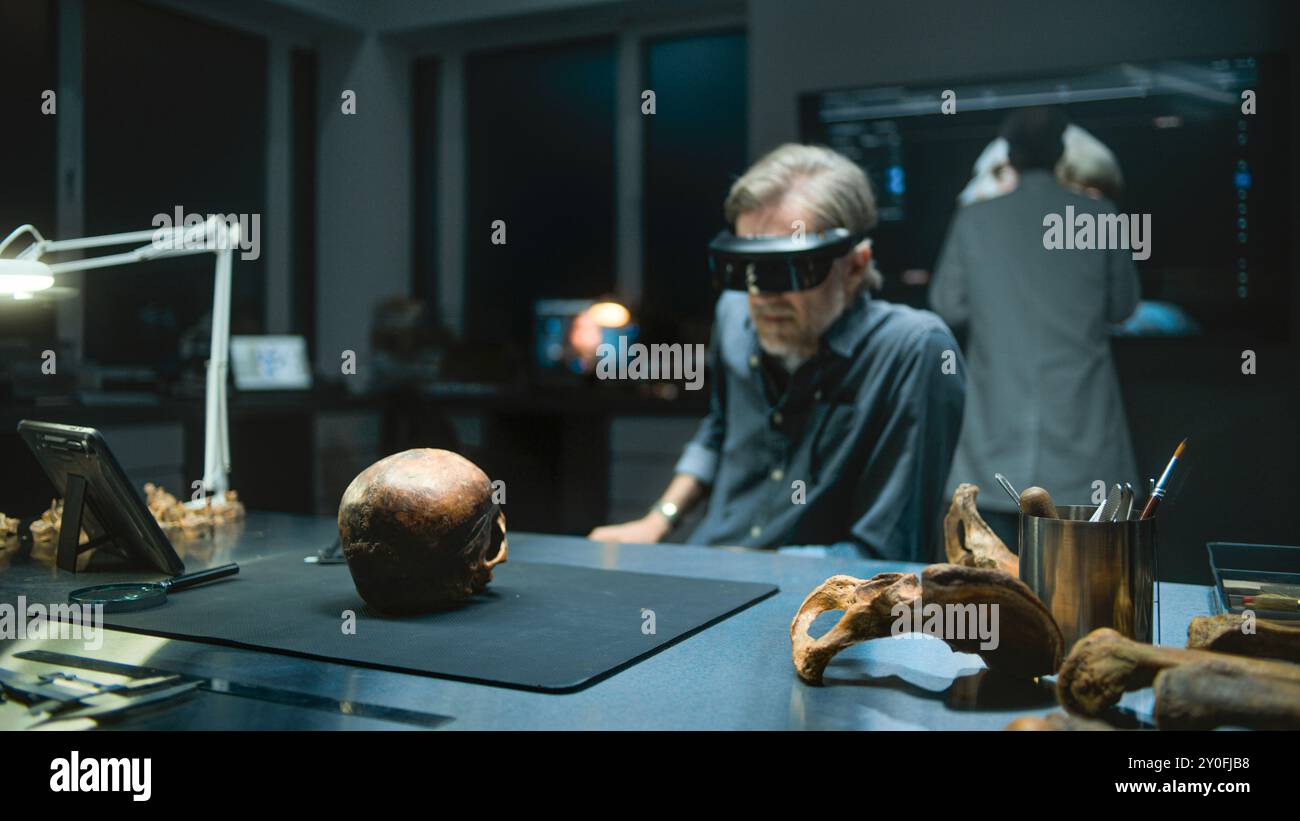 Archaeological lab at night: Mature archaeologist in AR headset studies ...