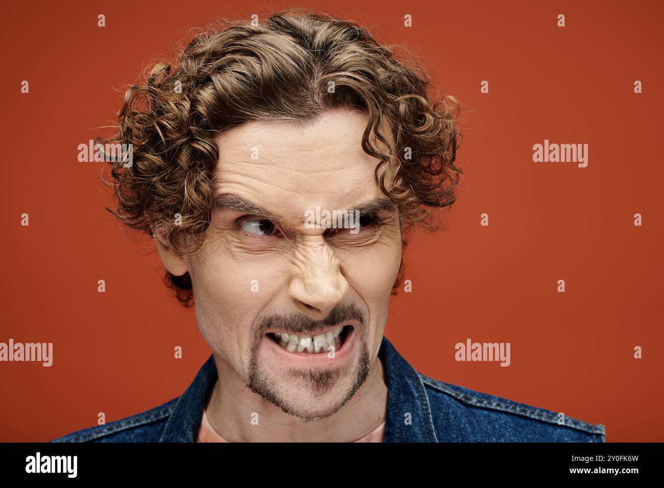 A man displays intense emotion while posing on a bright backdrop Stock ...