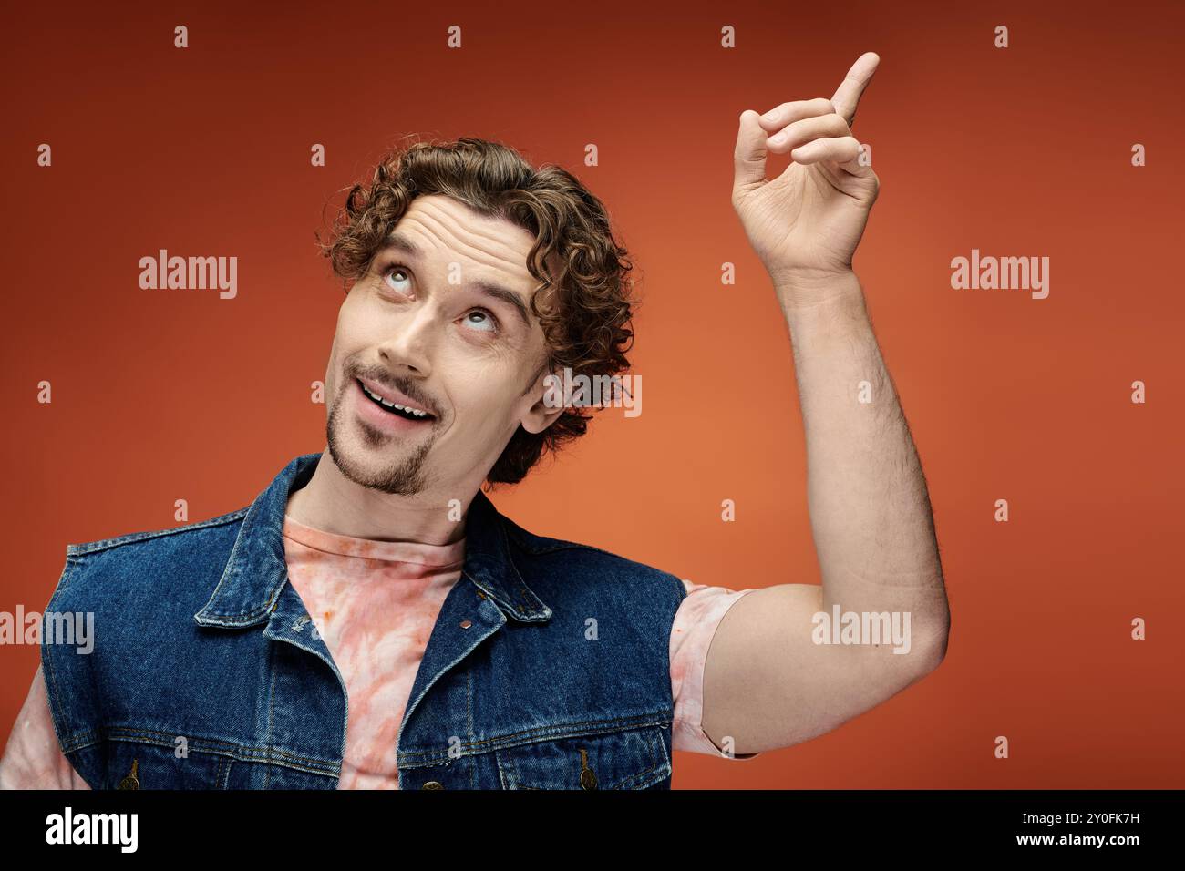 A spirited man joyfully points upward with a bright smile Stock Photo ...