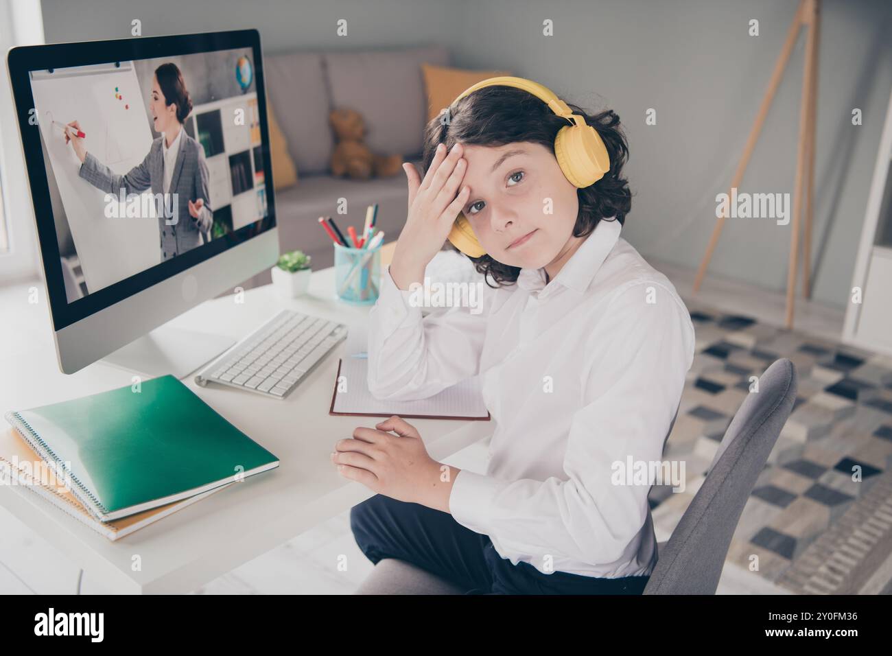 Photo of cute adorable little boy schoolkid sitting desk touch head ...