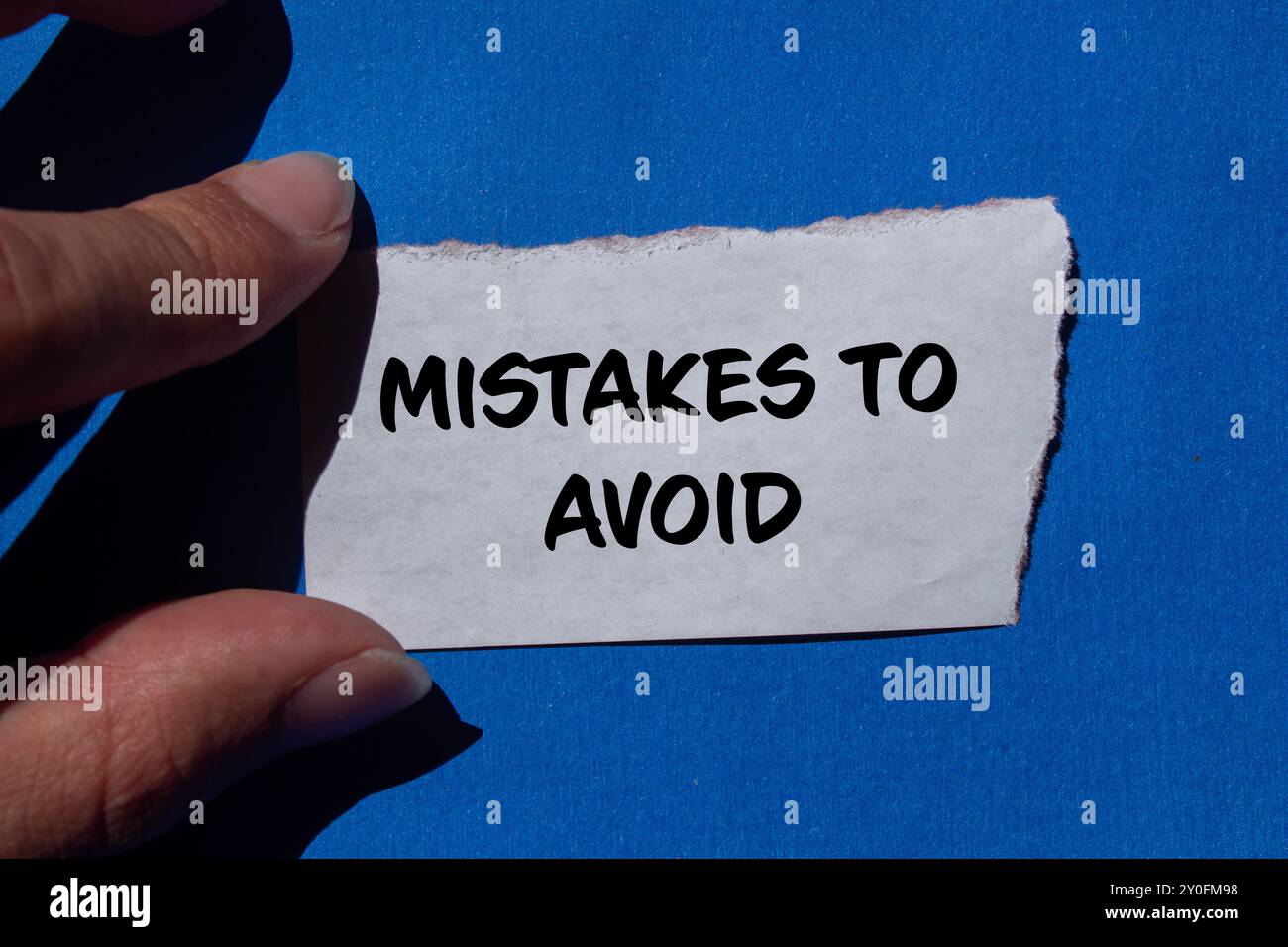 Mistakes to avoid message written on ripped torn paper with blue ...