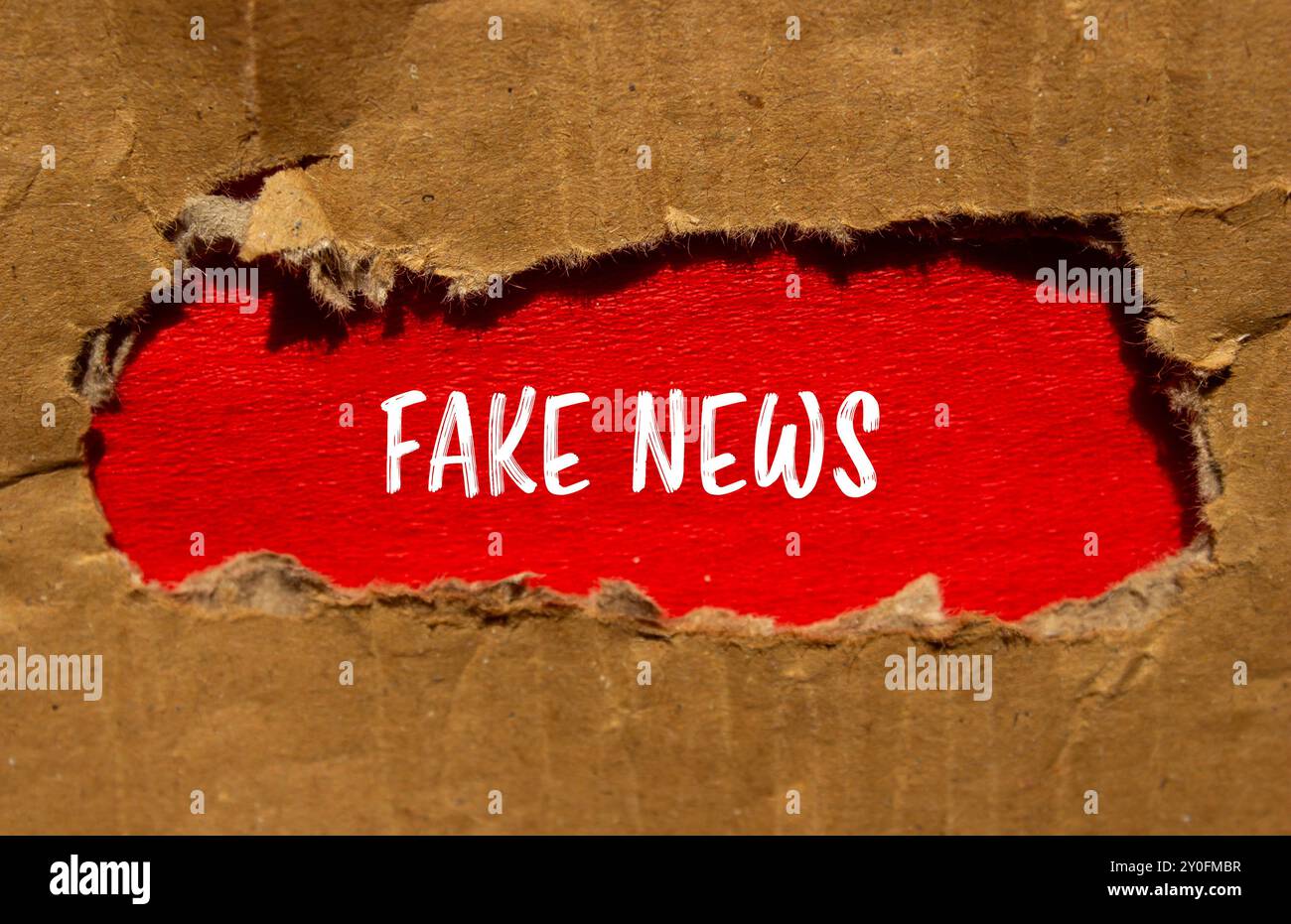 Fake news message written on torn cardboard paper with red background ...
