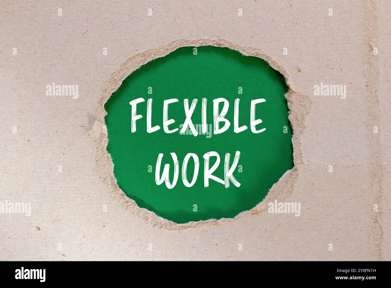 Flexible work message written on ripped torn paper with green background. Conceptual flexible ...