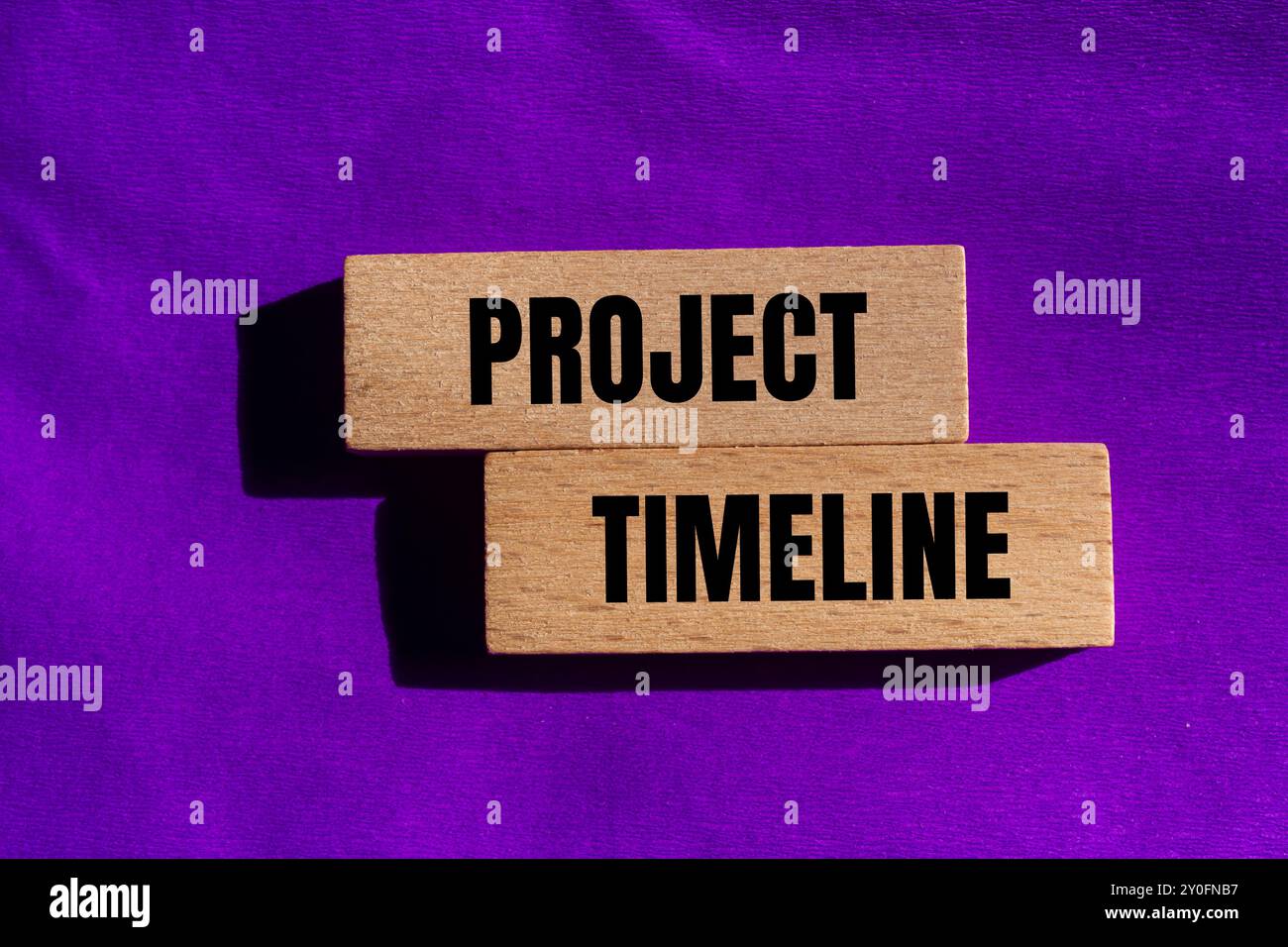 Project timeline message written on wooden blocks with purple background. Conceptual project ...