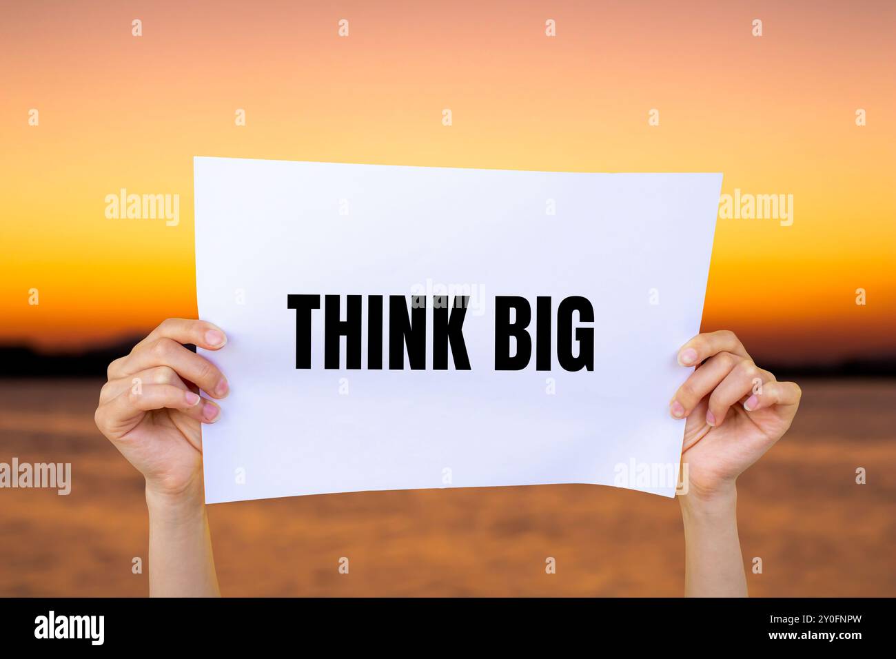 Think big message written on white paper with blurry lake background ...