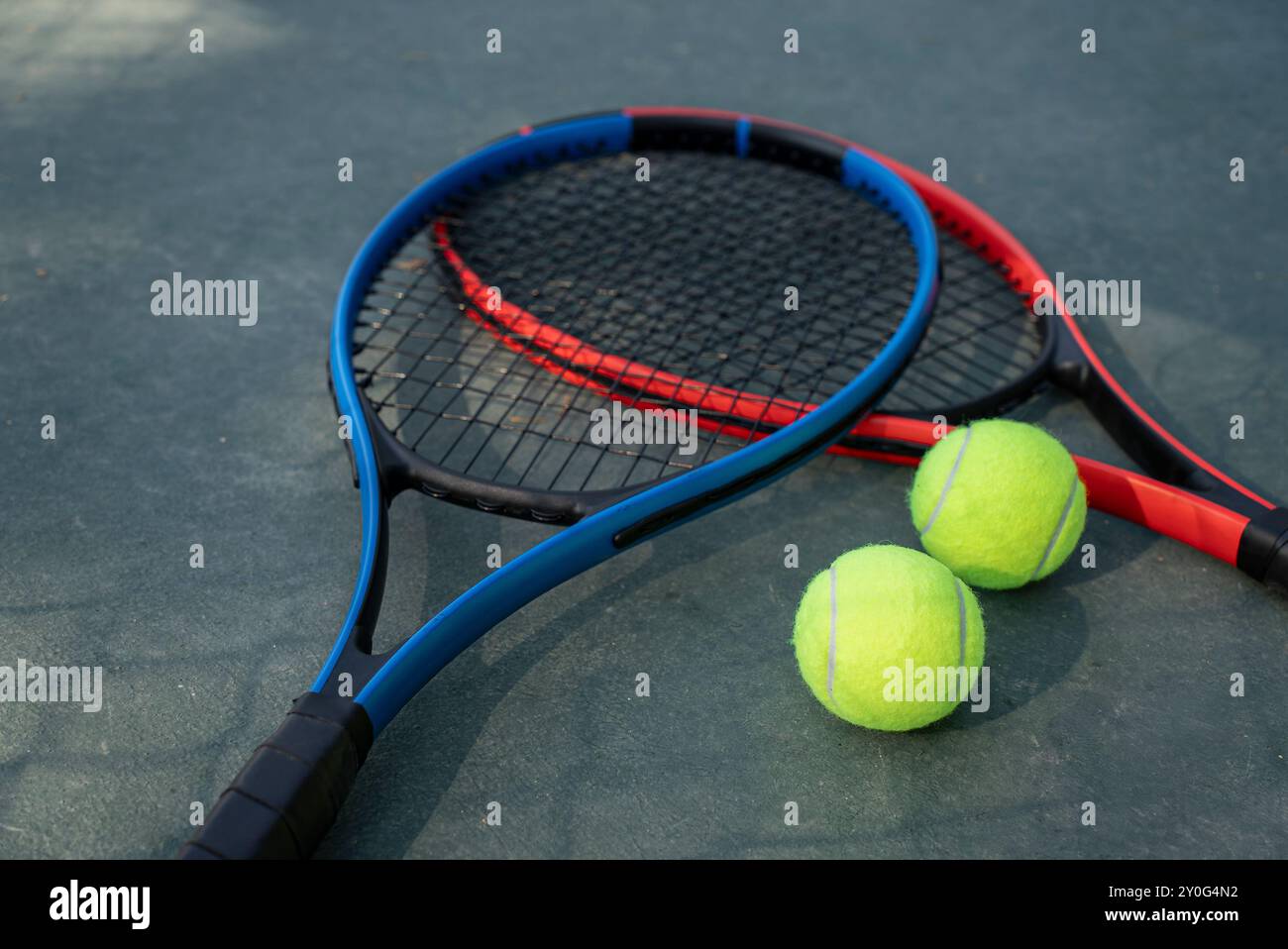 Red and blue tennis rackets with two yellow tennis balls laying on the ...