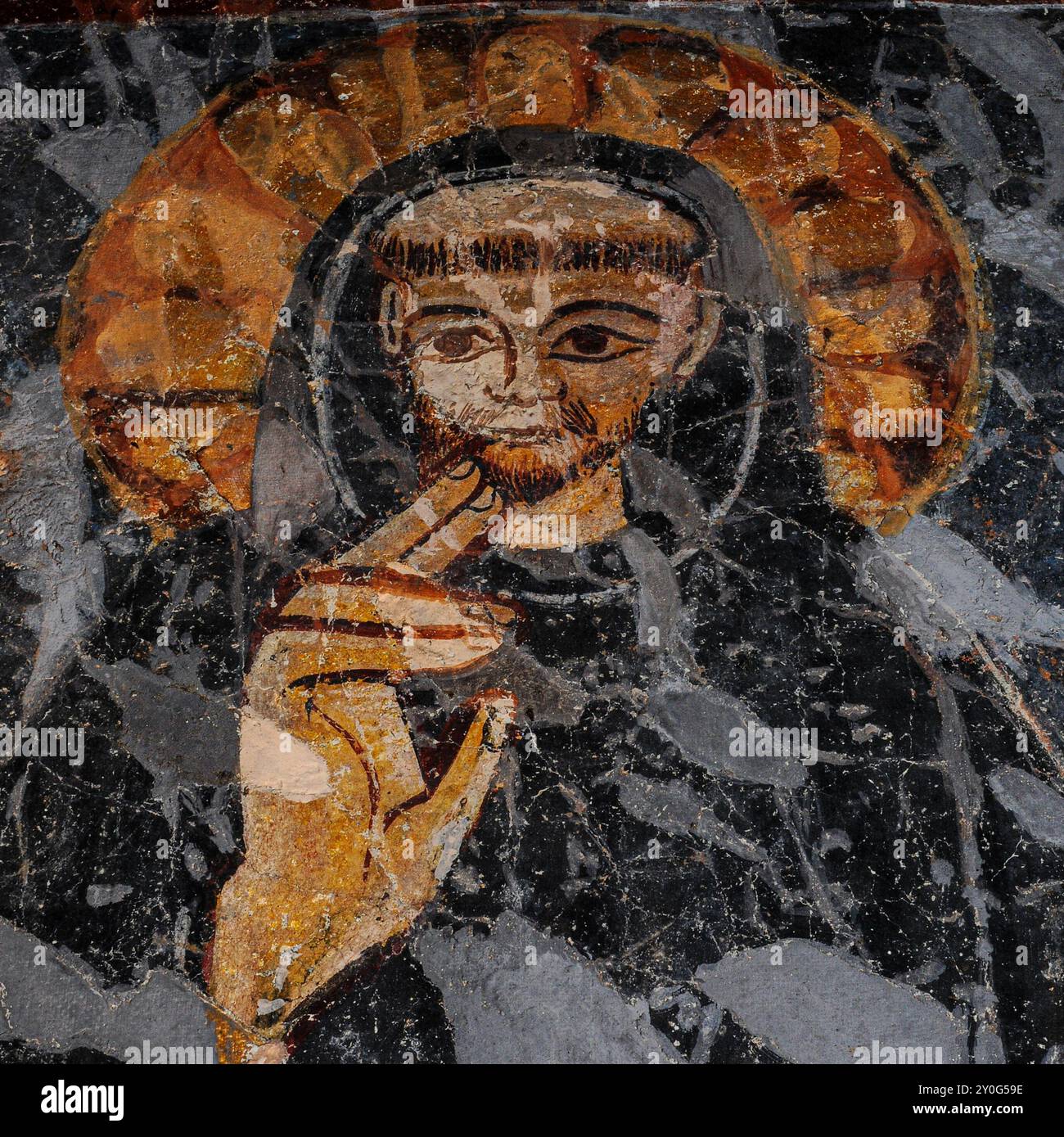 Face of a tonsured saintly monk, large and out of proportion right hand ...