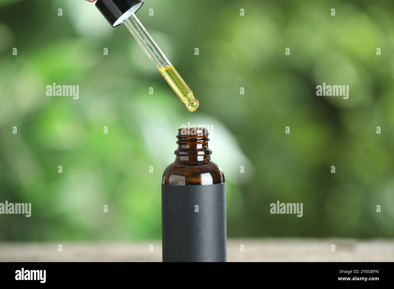 Dripping tincture from pipette into bottle against blurred green ...