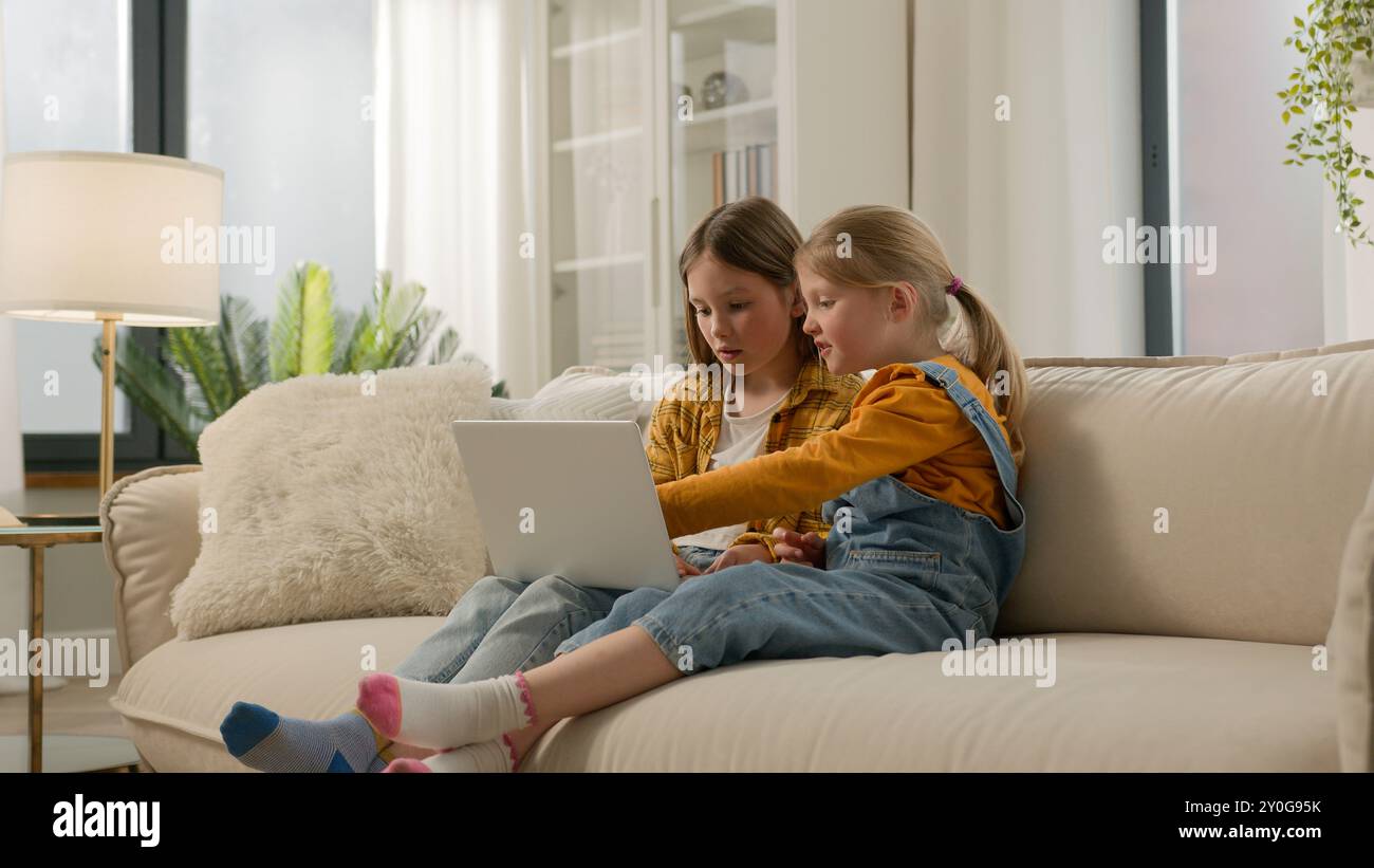 Carefree Caucasian kids daughters family girls watching movie funny cartoon on laptop computer ...