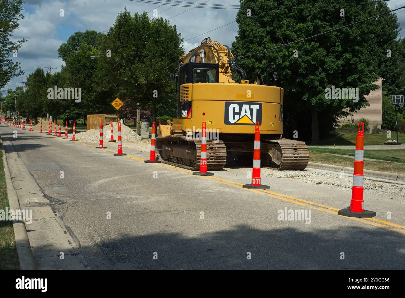 An excavator and other equipment sit in a coned-off section of street ...
