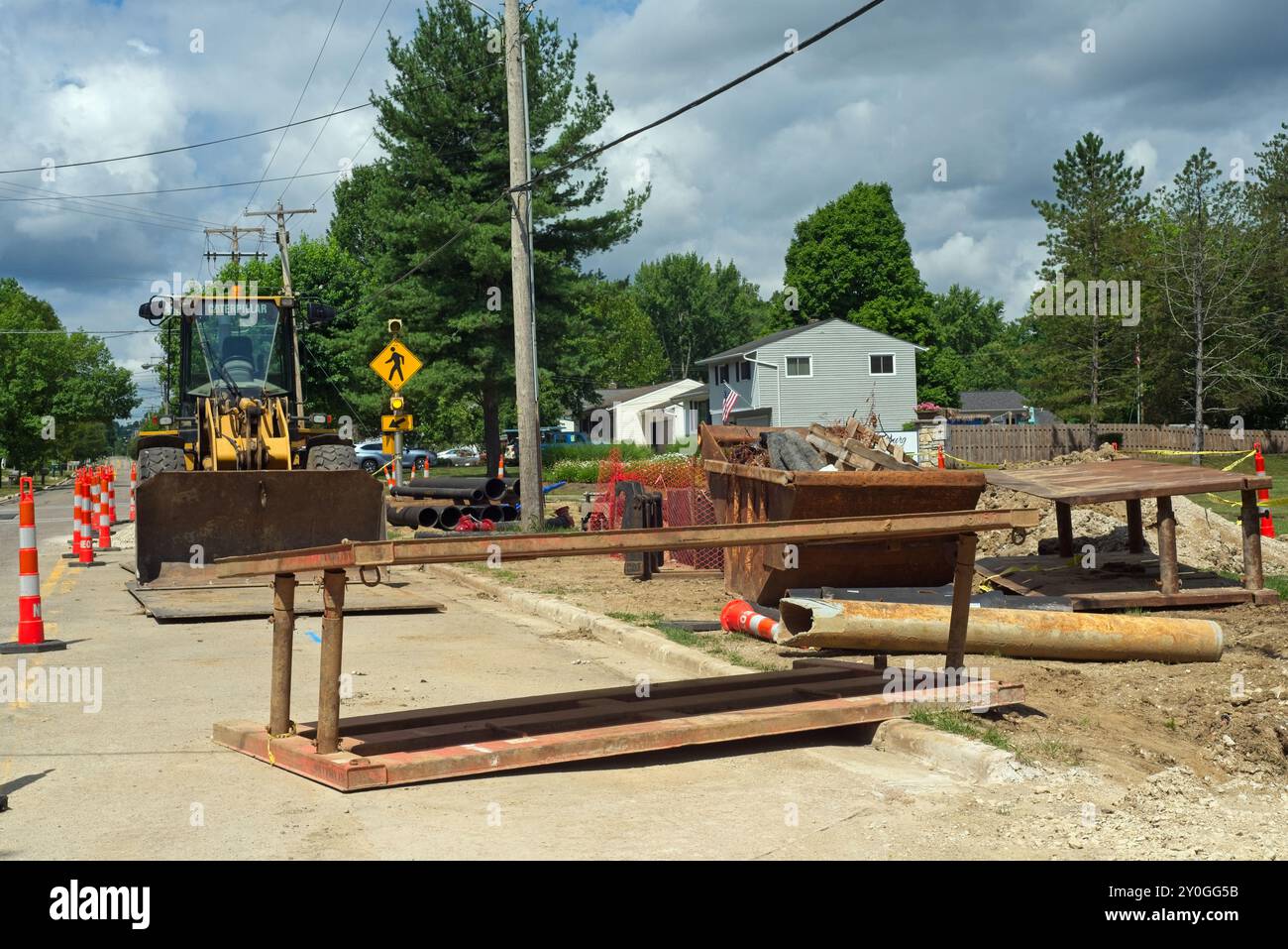 Road construction materials, including a front loader in the road and ...
