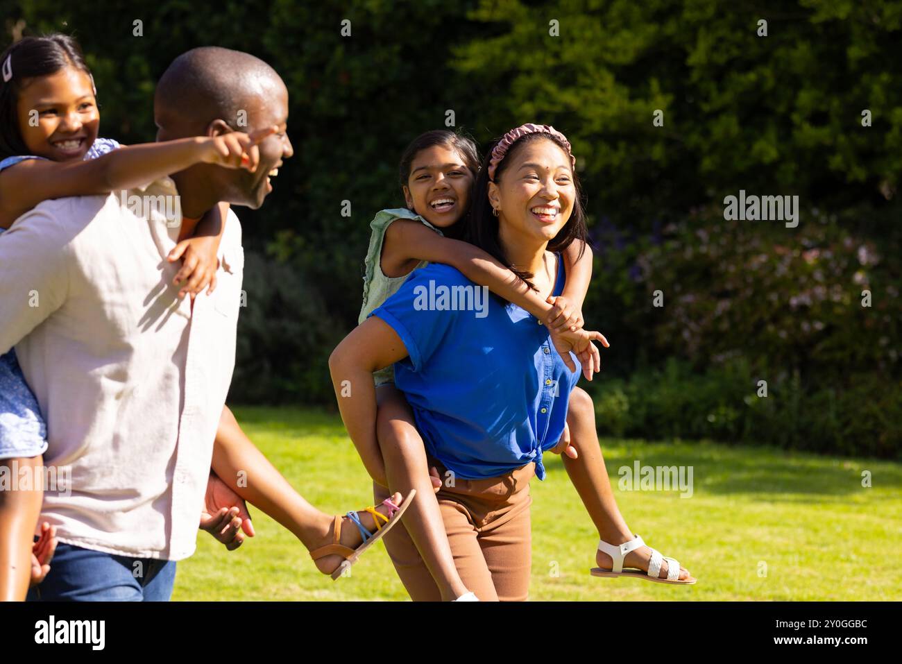 family giving piggyback rides to daughters, enjoying family time ...