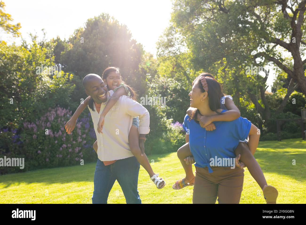 Playing in garden, multiracial parents giving piggyback rides to ...