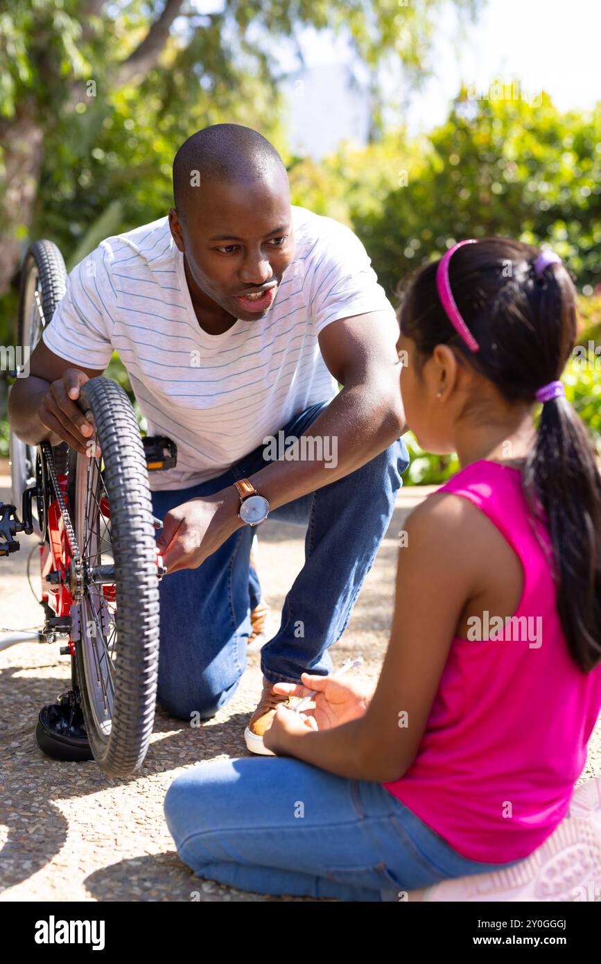 Fixing bicycle, father teaching daughter how to repair bike outdoors ...