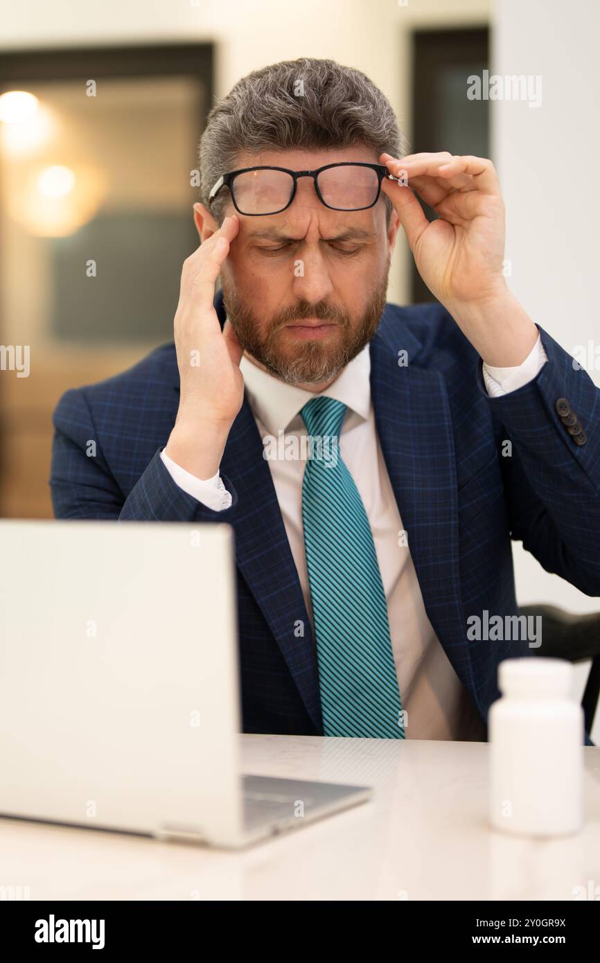 Headache and eye strain on laptop. Business man with stress and fatigue eyestrain. Businessman ...