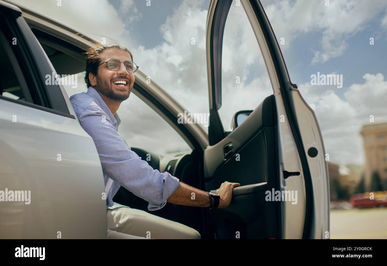 Positive young middle-eastern man going out the car Stock Photo - Alamy