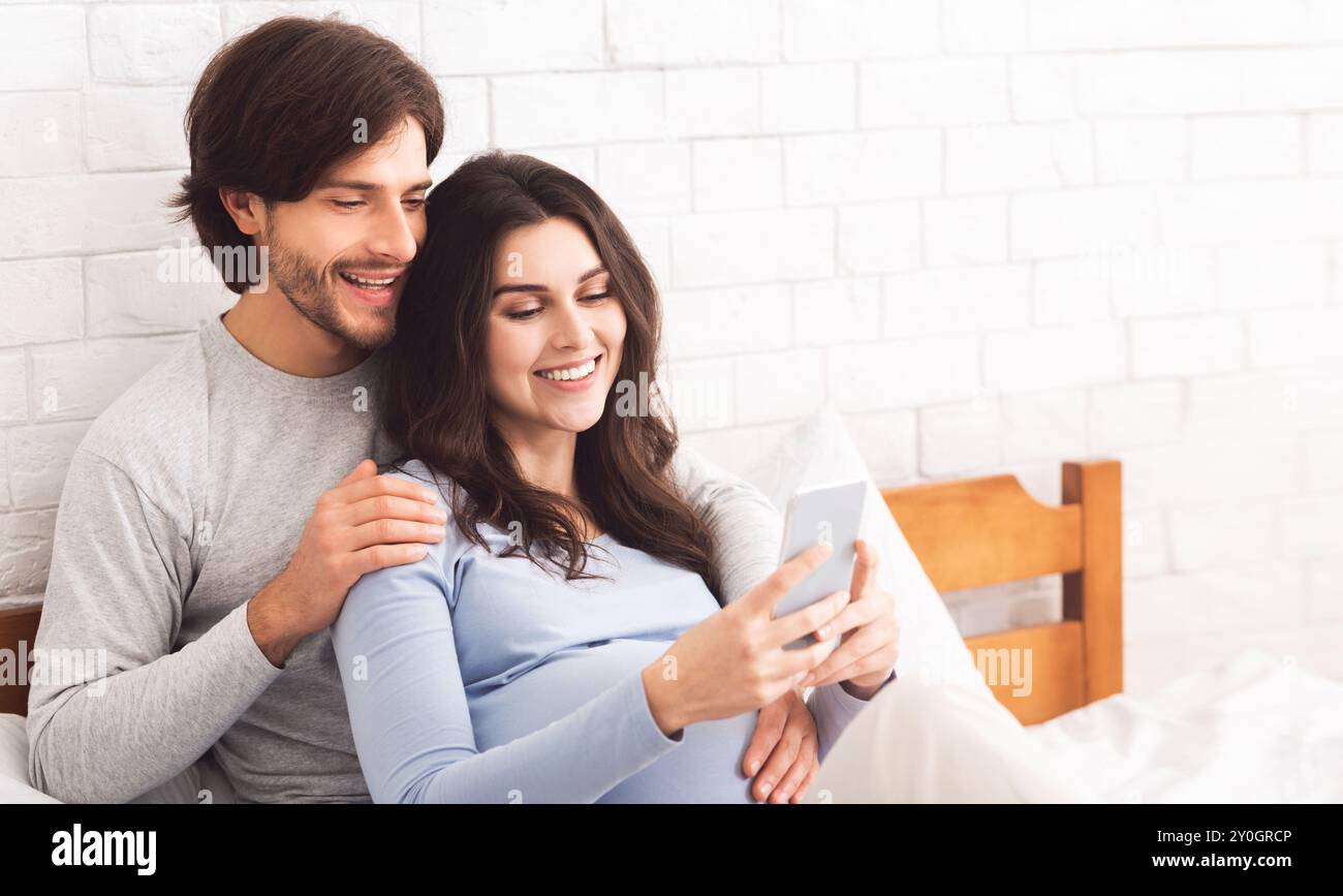 Happy expecting couple posing for selfie, cuddling in bed at home Stock ...