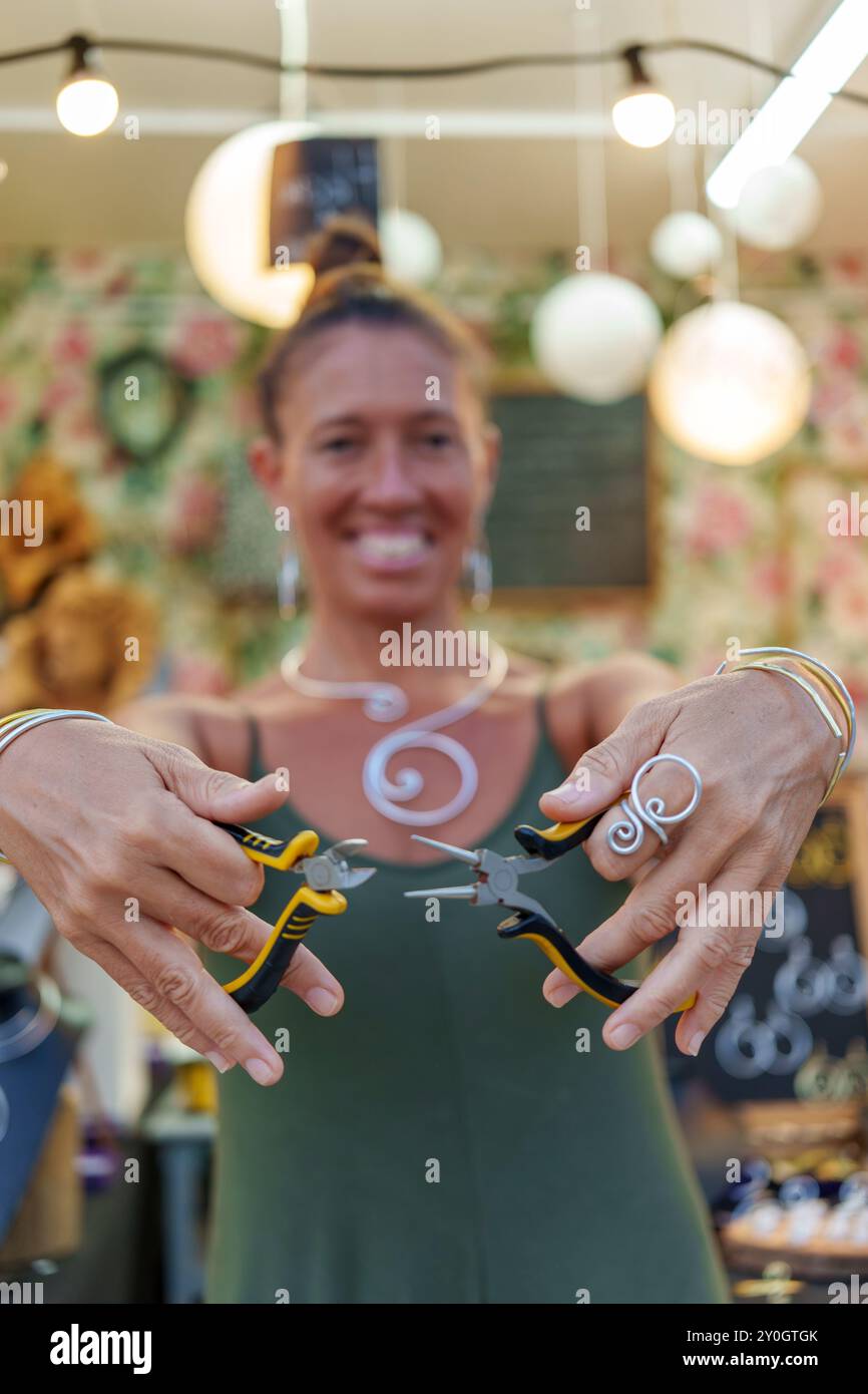 Proud Hispanic Woman in Her 50s Posing with Tools in Hand in Front of Her Street Stall Selling ...