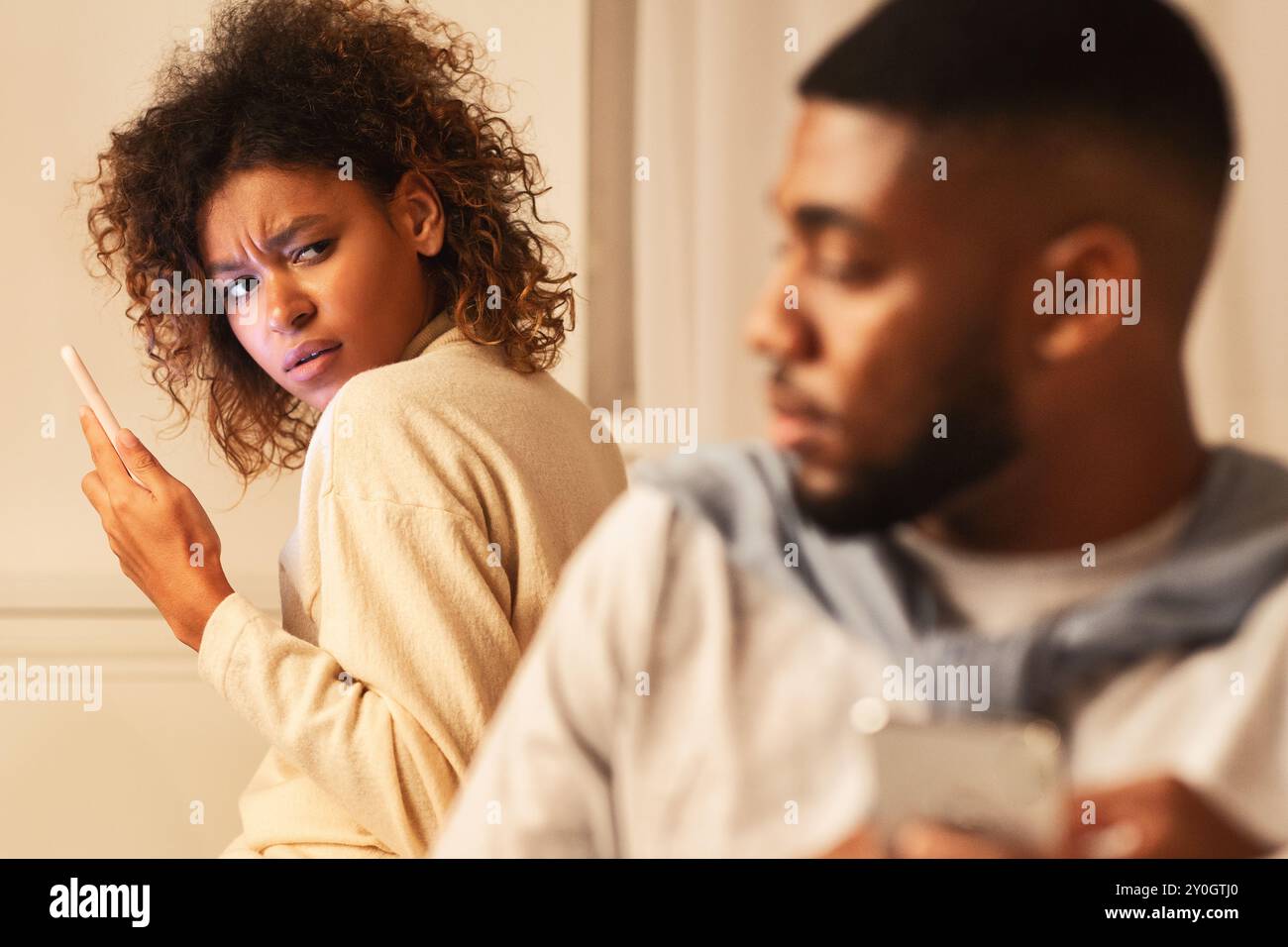 Afro woman suspecting husband in betrayal, looking at man Stock Photo ...