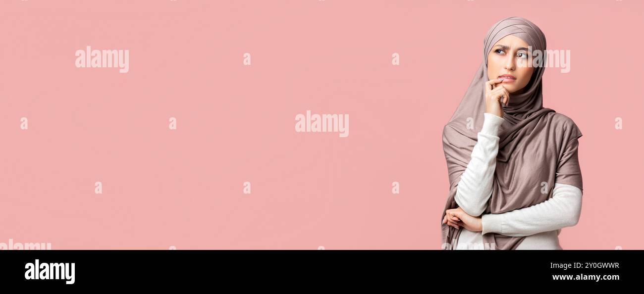 Pensive muslim girl thinking and looking away on pink studio background ...