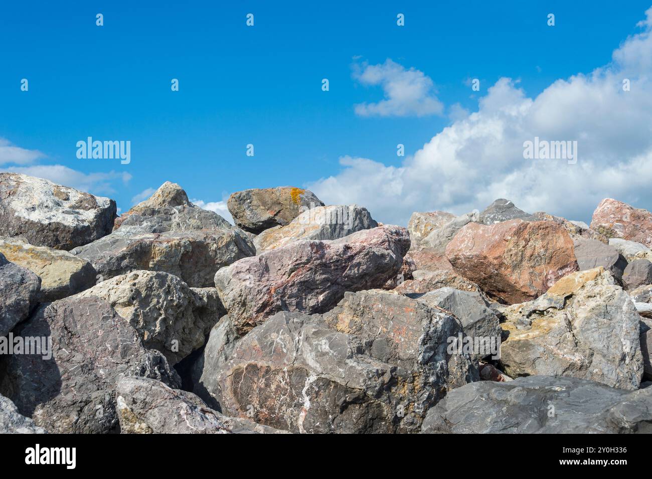 Pile of boulders. sea defence against a blue sky background Stock Photo ...