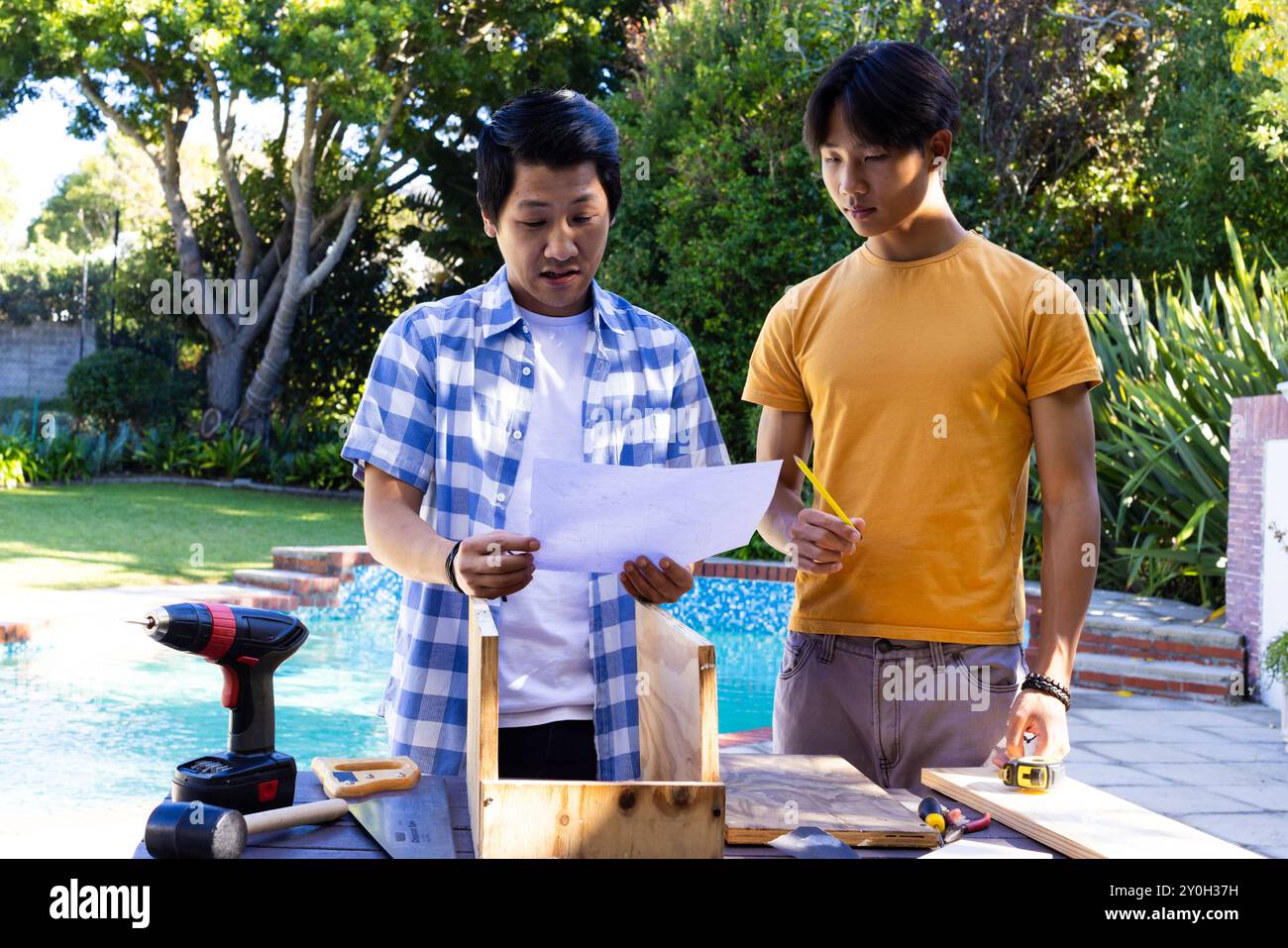 Building wooden project, Asian father and teenage son discussing plans ...